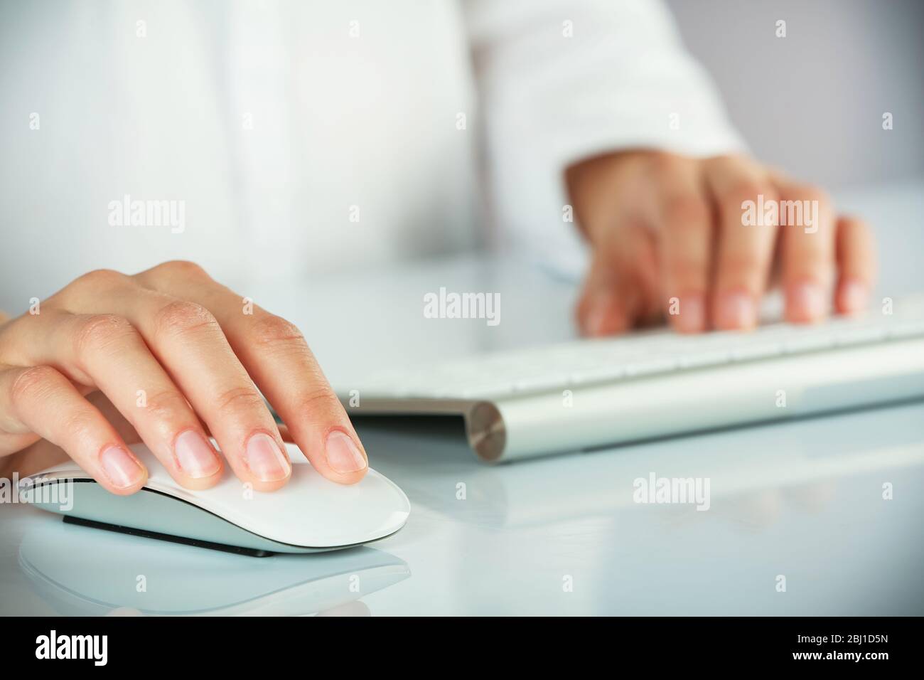 Female hands typing on keyboard and holding computer mouse on light ...