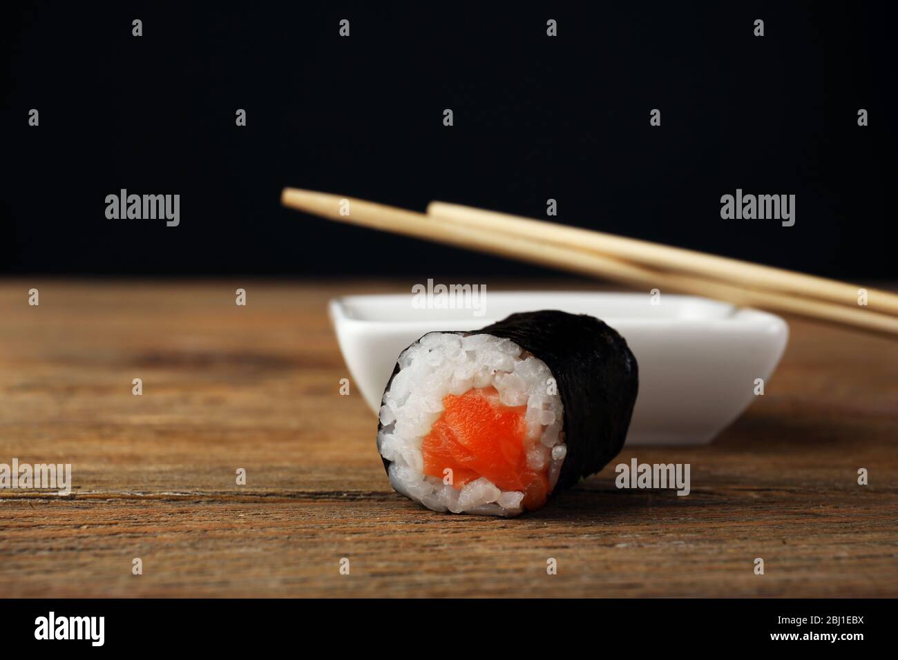 Roll with sauce and wooden sticks on dark background Stock Photo - Alamy