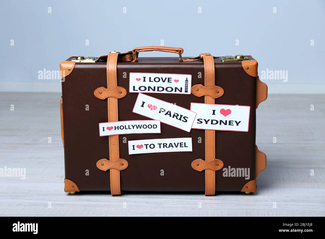 Suitcase with stickers on floor in room Stock Photo - Alamy