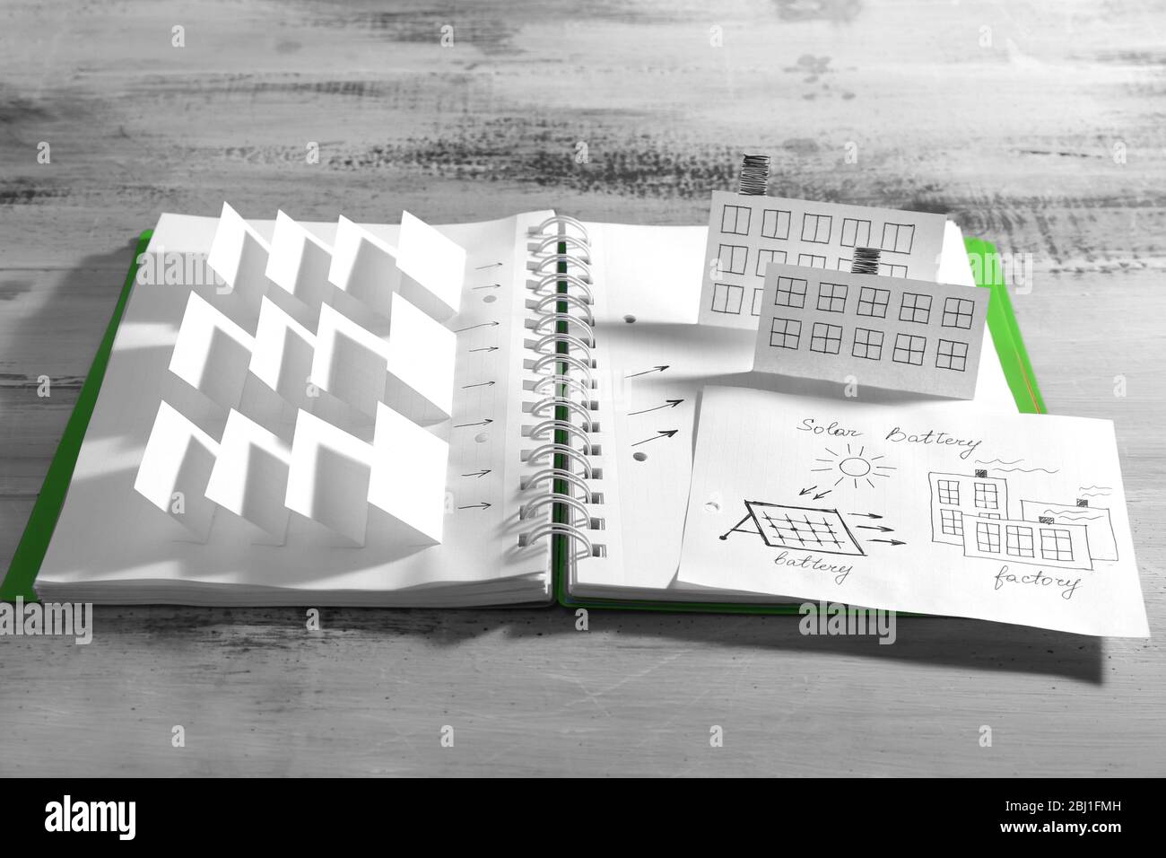 Handmade model of solar panels in notebook on wooden table, closeup ...