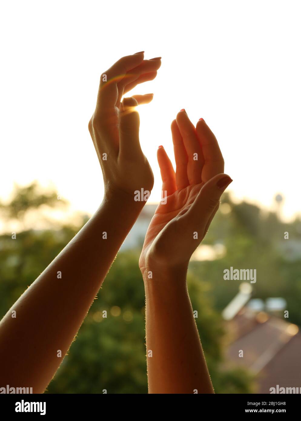 Female hands over sunset sky background Stock Photo - Alamy