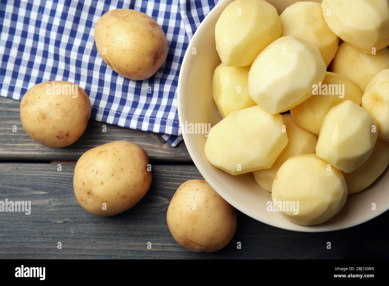 Peeled new potatoes in bowl on wooden table with napkin, top view Stock ...
