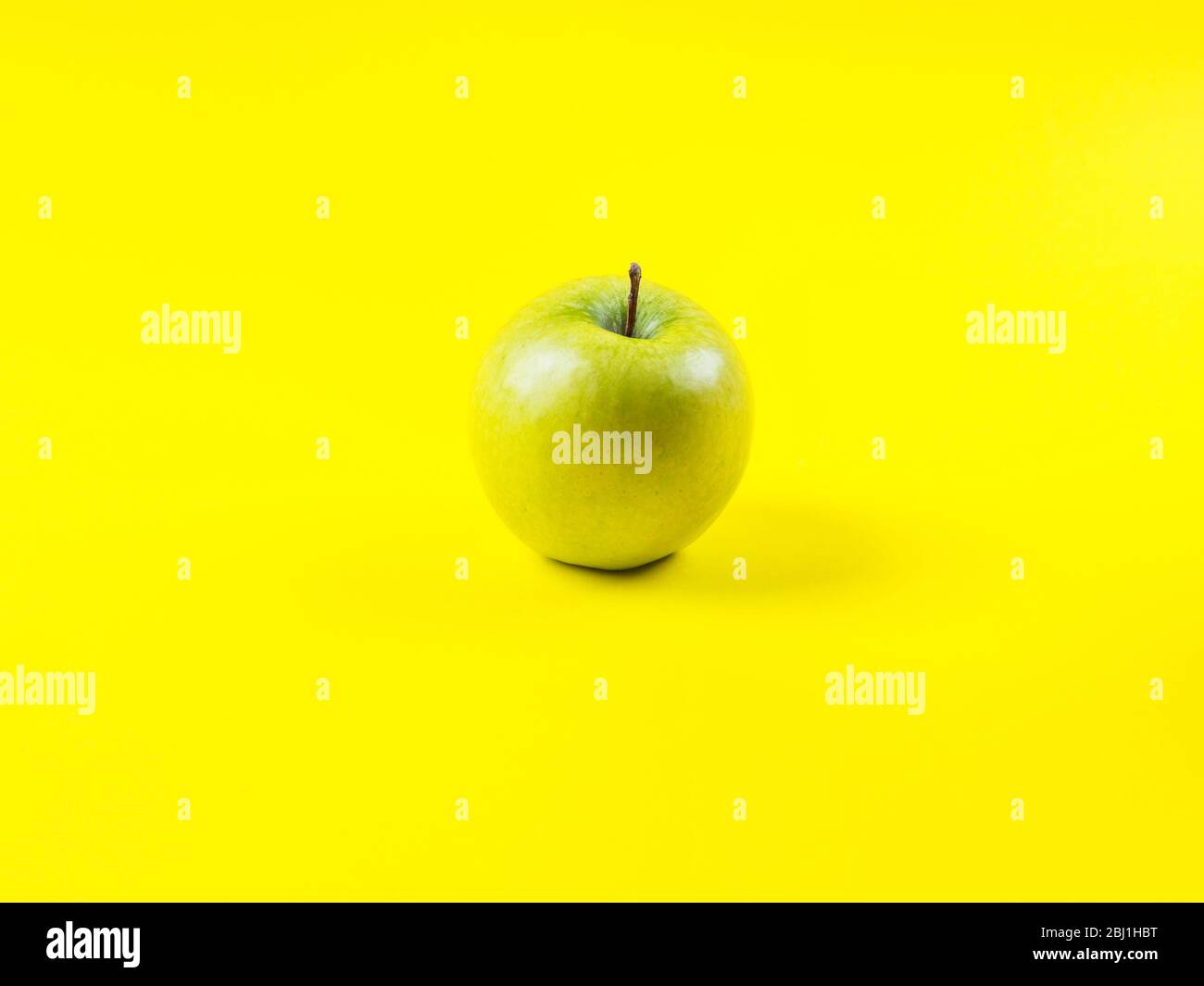 Shiny green apple on bold yellow background Stock Photo - Alamy