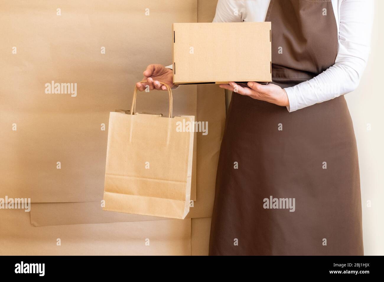 Packer's hands holding a Craft Paper Bag and Box. Worker dressed in ...