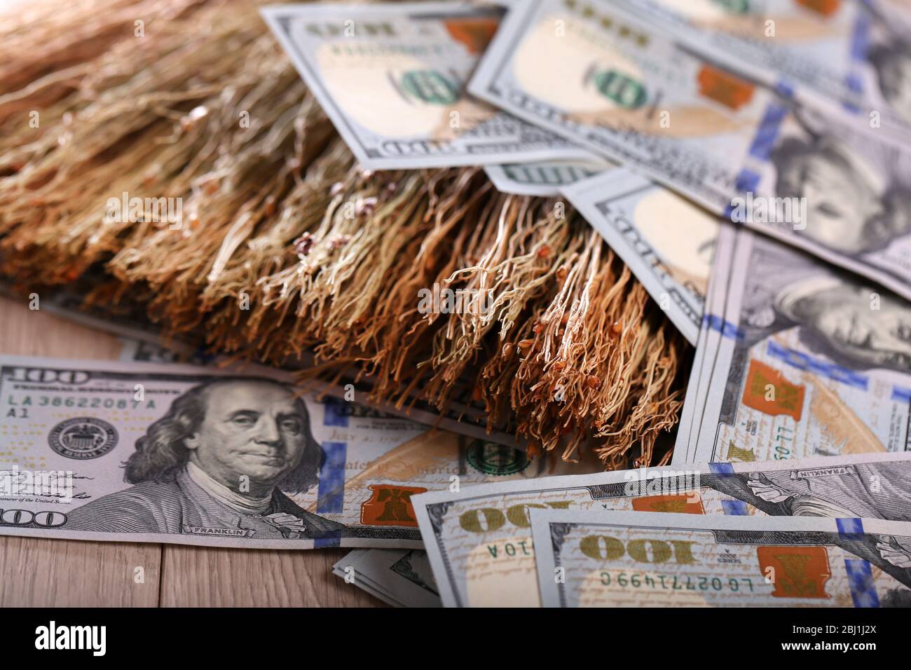 Dollars and broom on wooden floor, closeup Stock Photo - Alamy