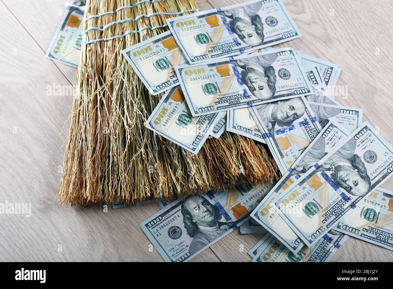 Dollars and broom on wooden floor, closeup Stock Photo - Alamy
