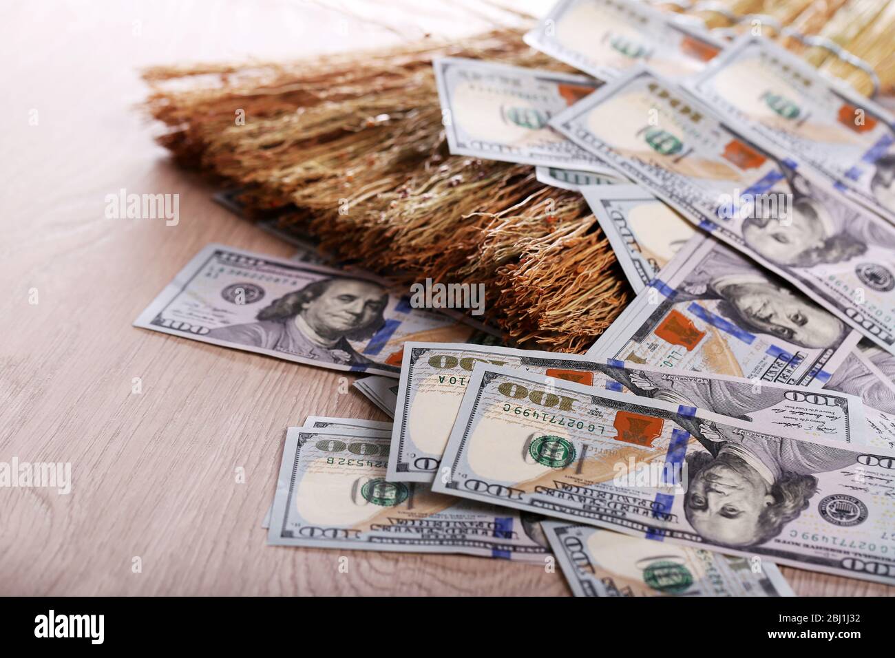 Dollars and broom on wooden floor, closeup Stock Photo - Alamy