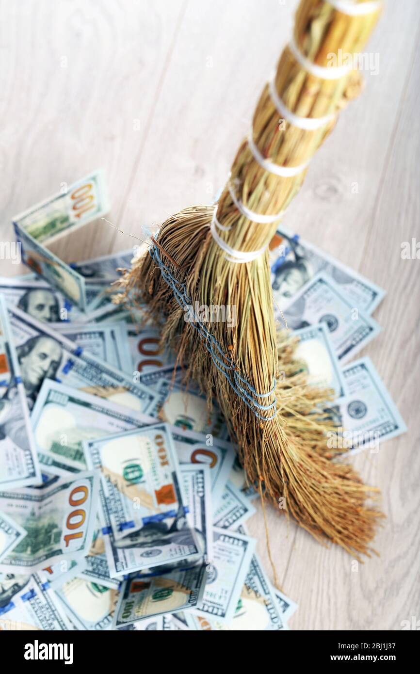 Dollars and broom on wooden floor, closeup Stock Photo - Alamy