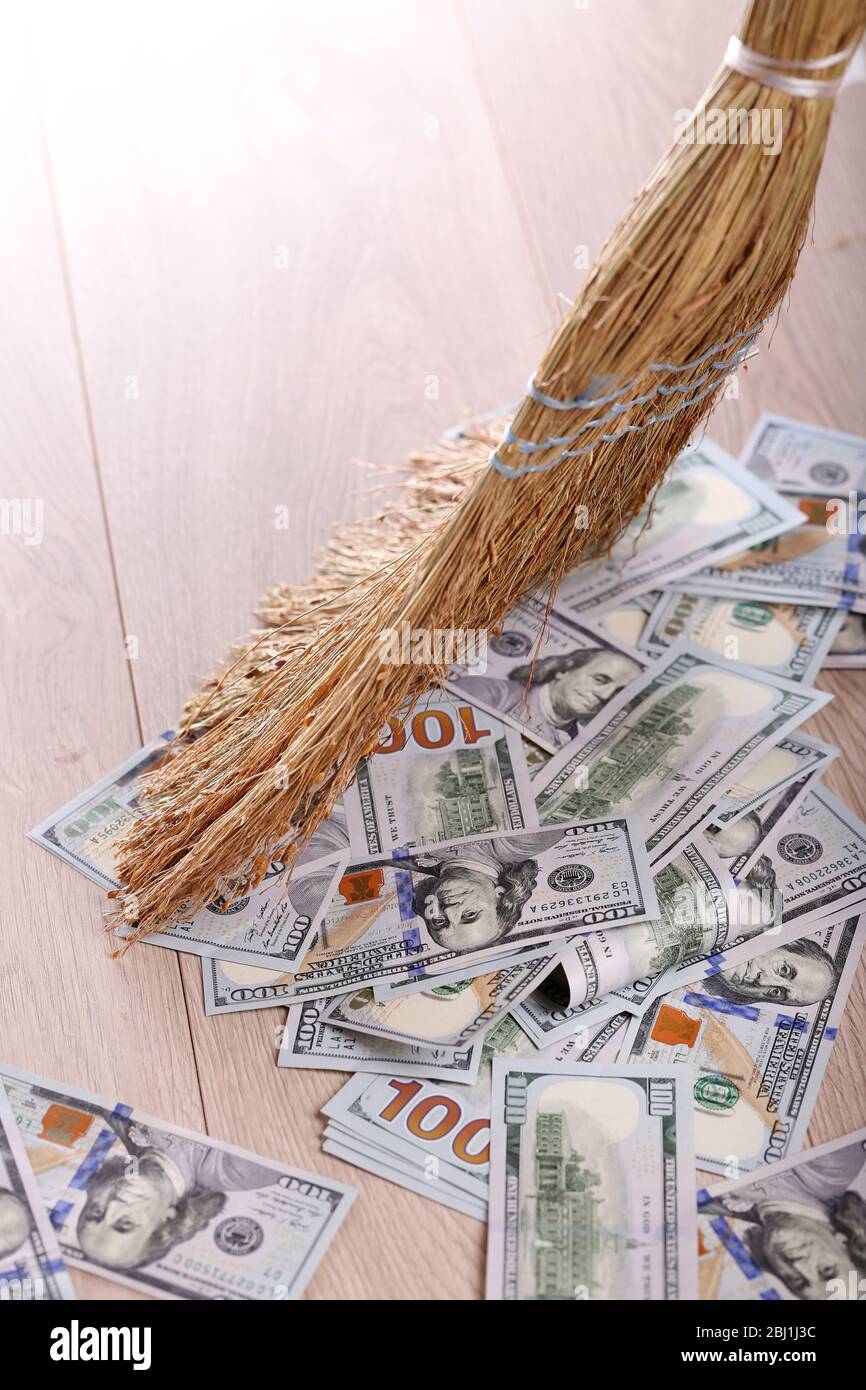 Dollars and broom on wooden floor, closeup Stock Photo - Alamy