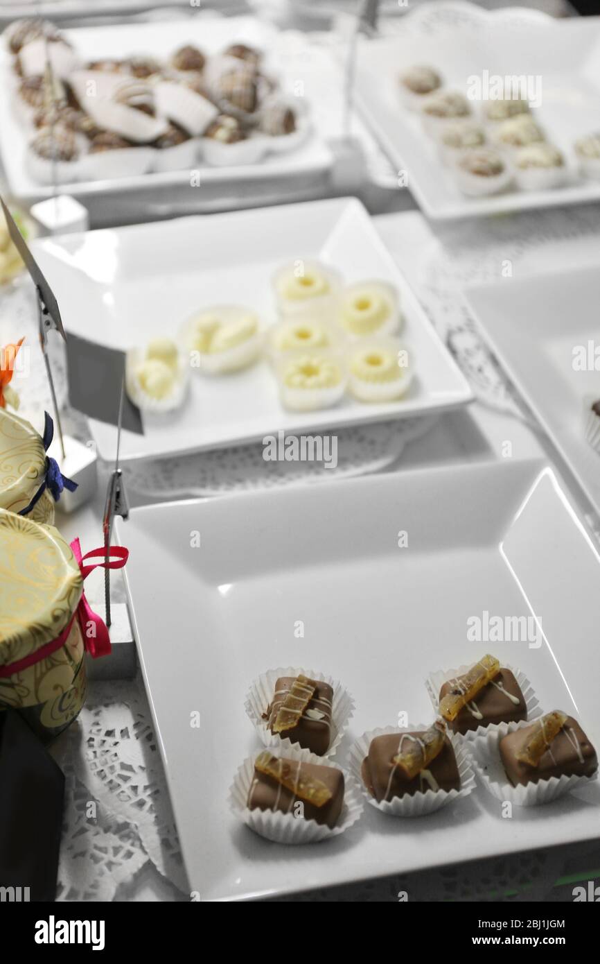 Delicious chocolate candies on plates on table close up Stock Photo - Alamy