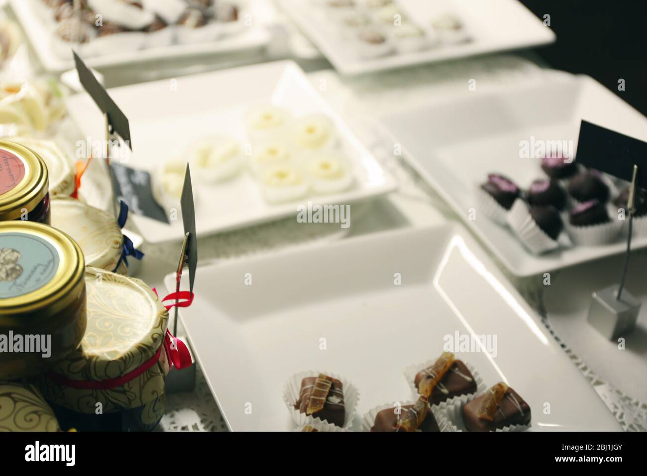 Delicious chocolate candies on plates on table close up Stock Photo - Alamy