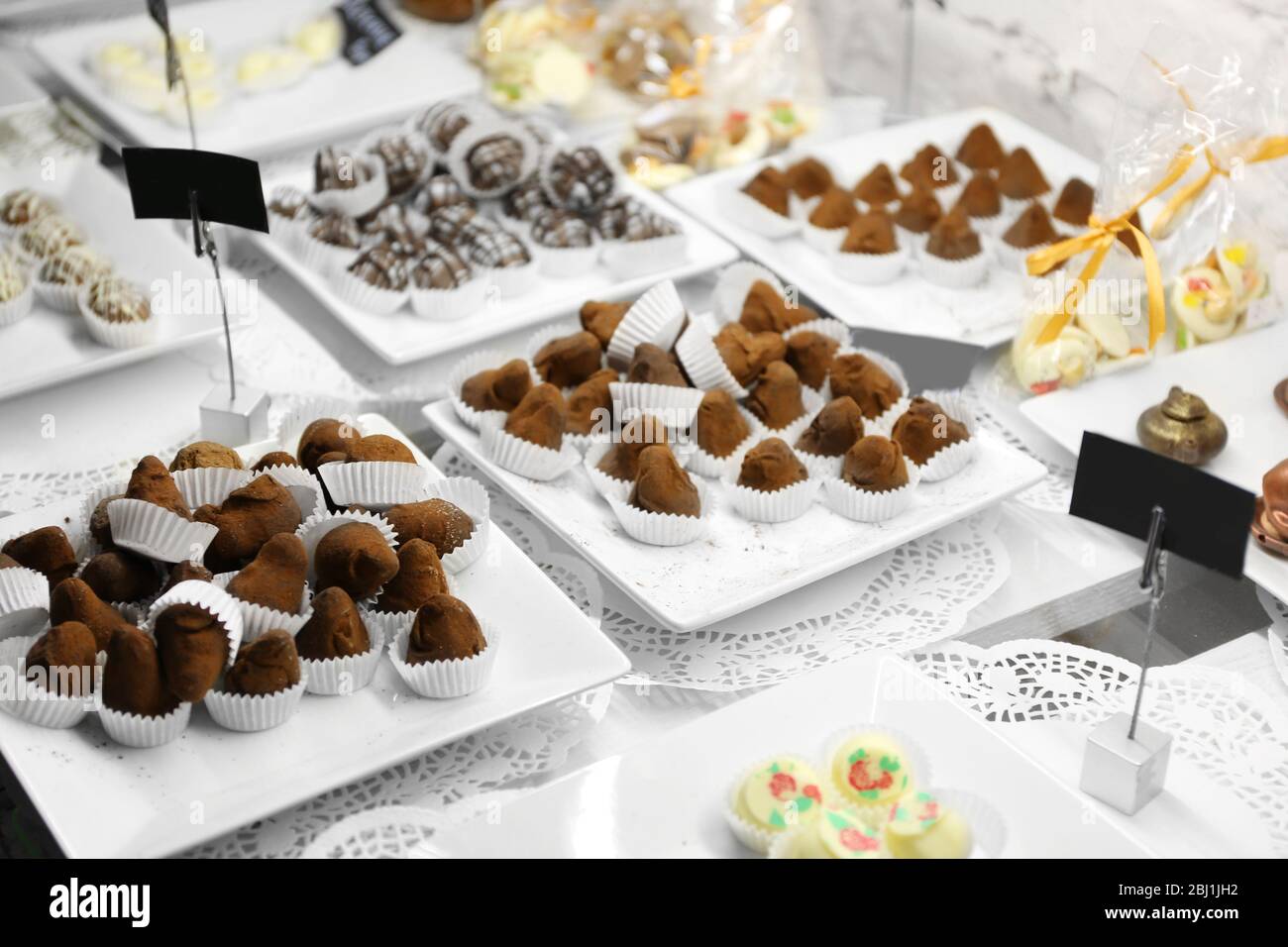 Delicious chocolate candies on plates on table close up Stock Photo - Alamy