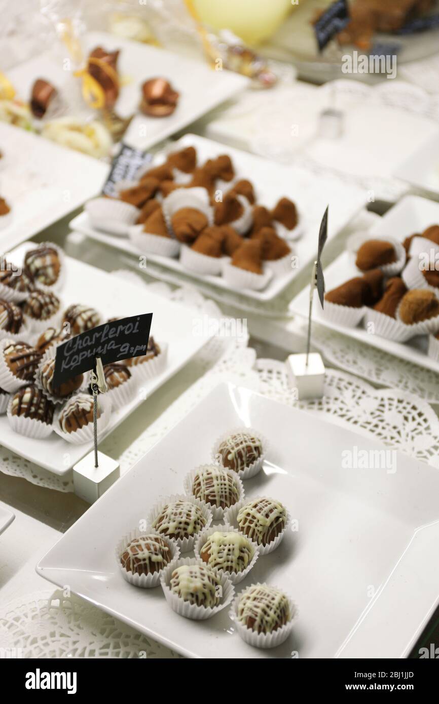 Delicious chocolate candies on plates on table close up Stock Photo - Alamy