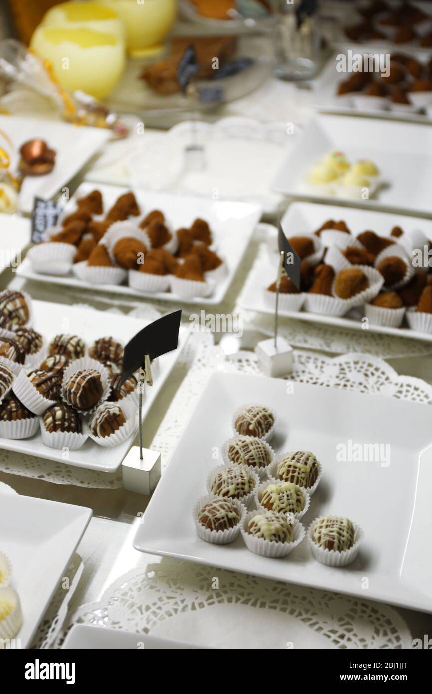 Delicious chocolate candies on plates on table close up Stock Photo - Alamy