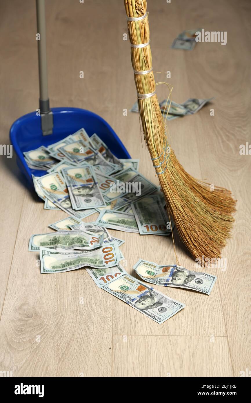 Broom sweeps dollars in garbage scoop on wooden floor background Stock ...