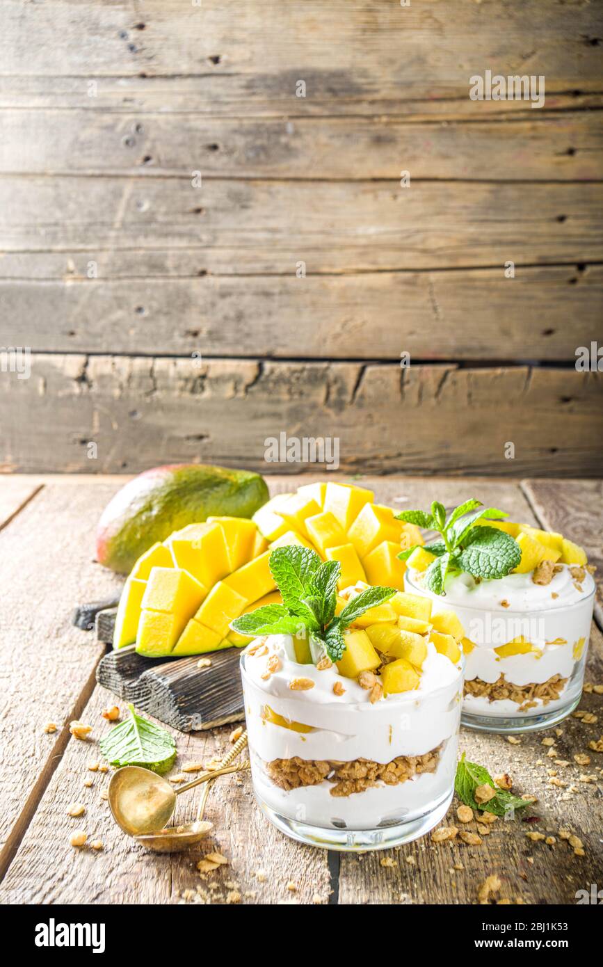 Summer breakfast layered dessert with mango and granola. Mango parfaits ...