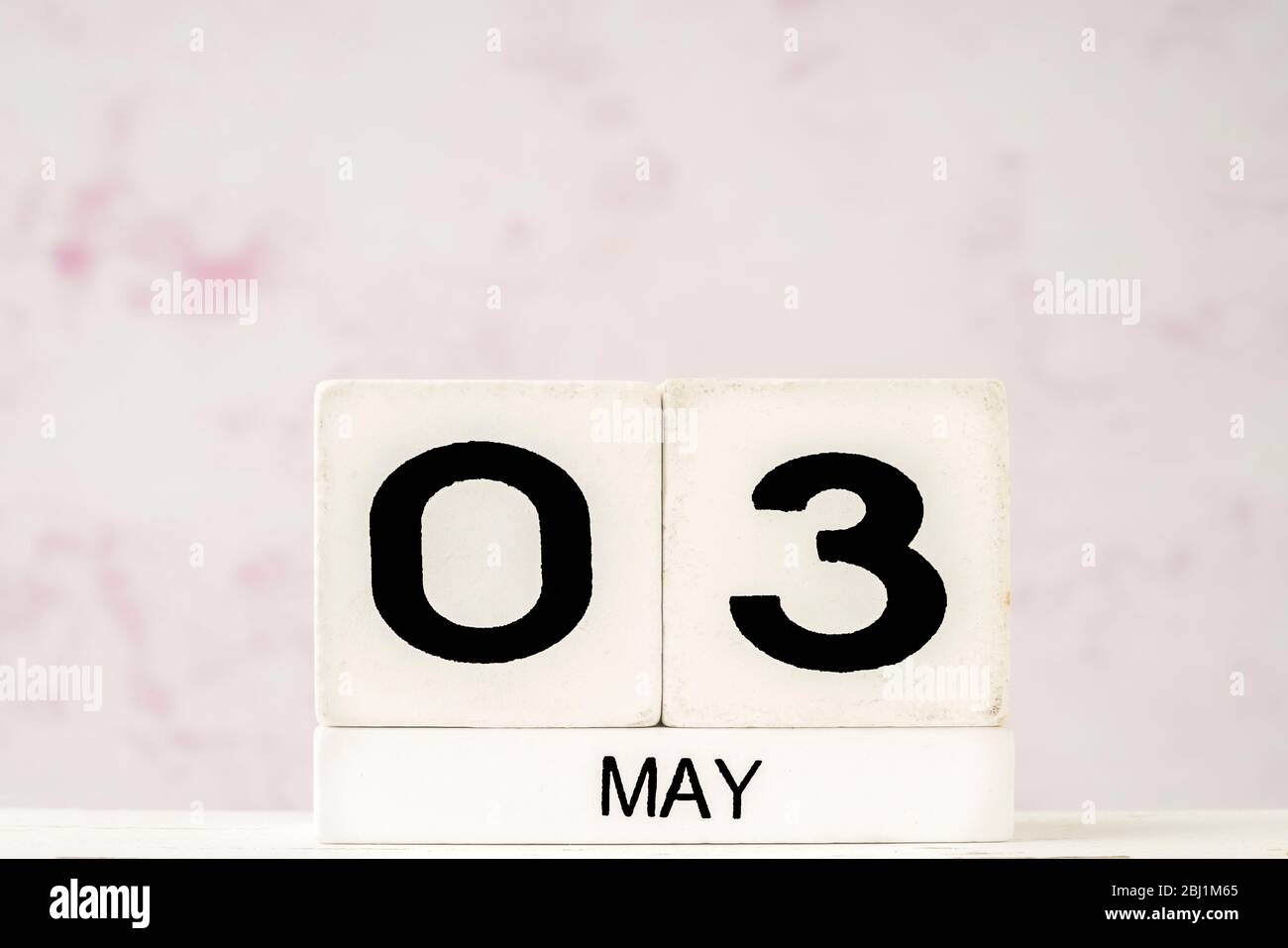 White cube calendar for May against soft pink background with copy ...