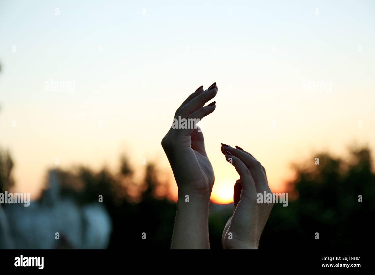 Female hands over sunset sky background Stock Photo - Alamy