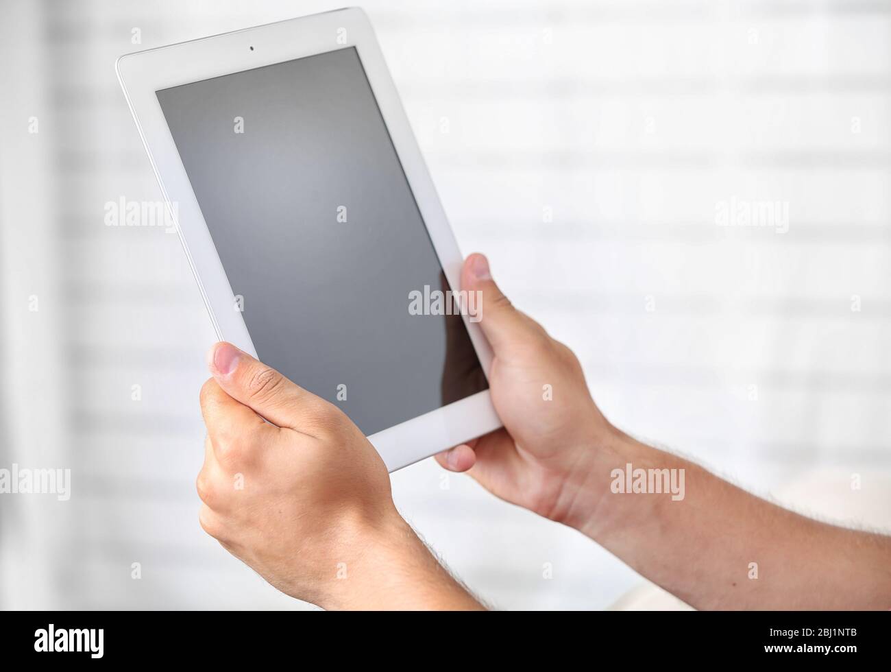 Male hand holding PC tablet on home interior background Stock Photo - Alamy
