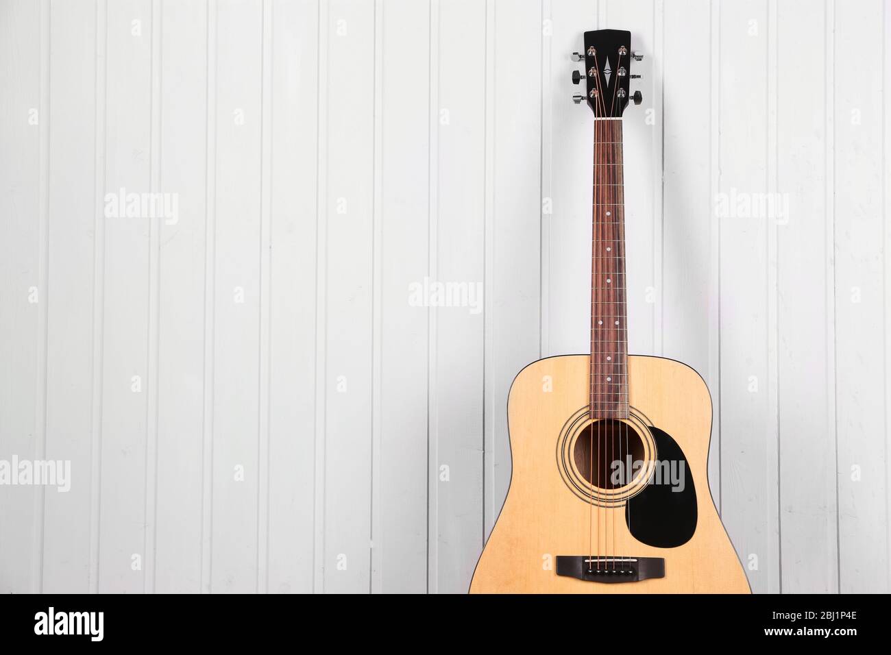 Classical guitar on white wooden wall background Stock Photo - Alamy
