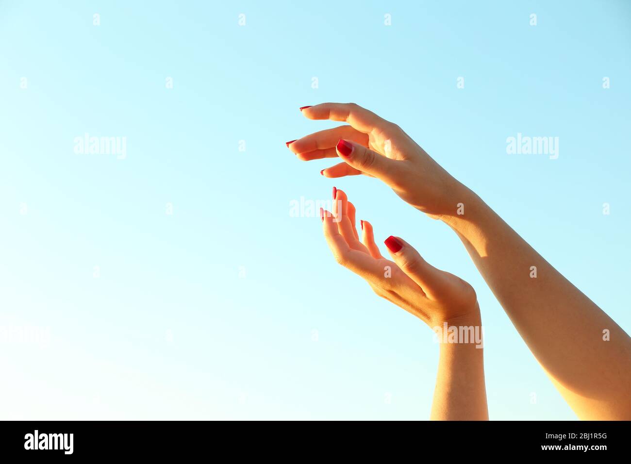 Female hands over blue sky background Stock Photo - Alamy