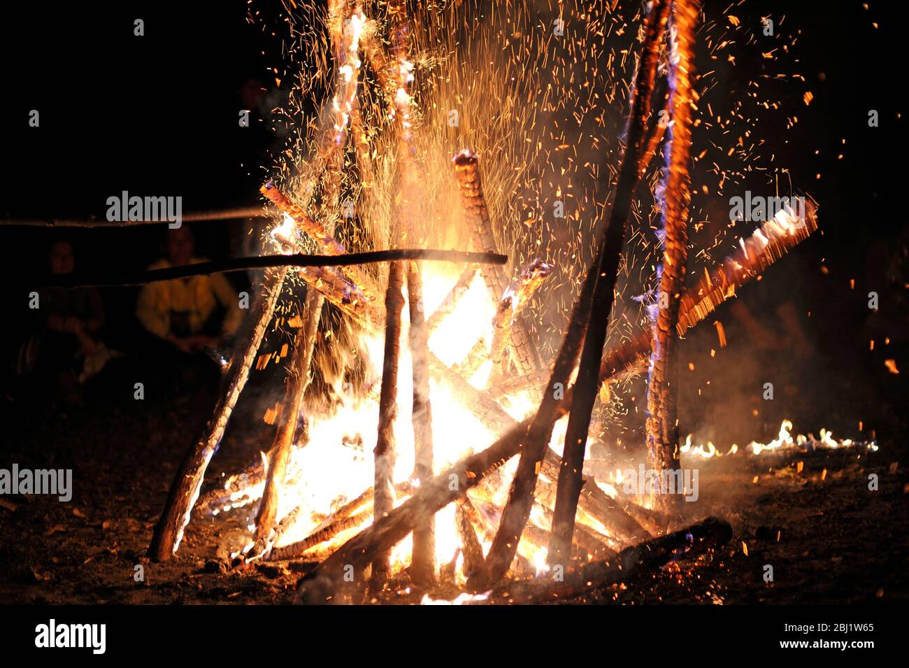 Big fire set in the forest, blurred people on the background. Meeting ...