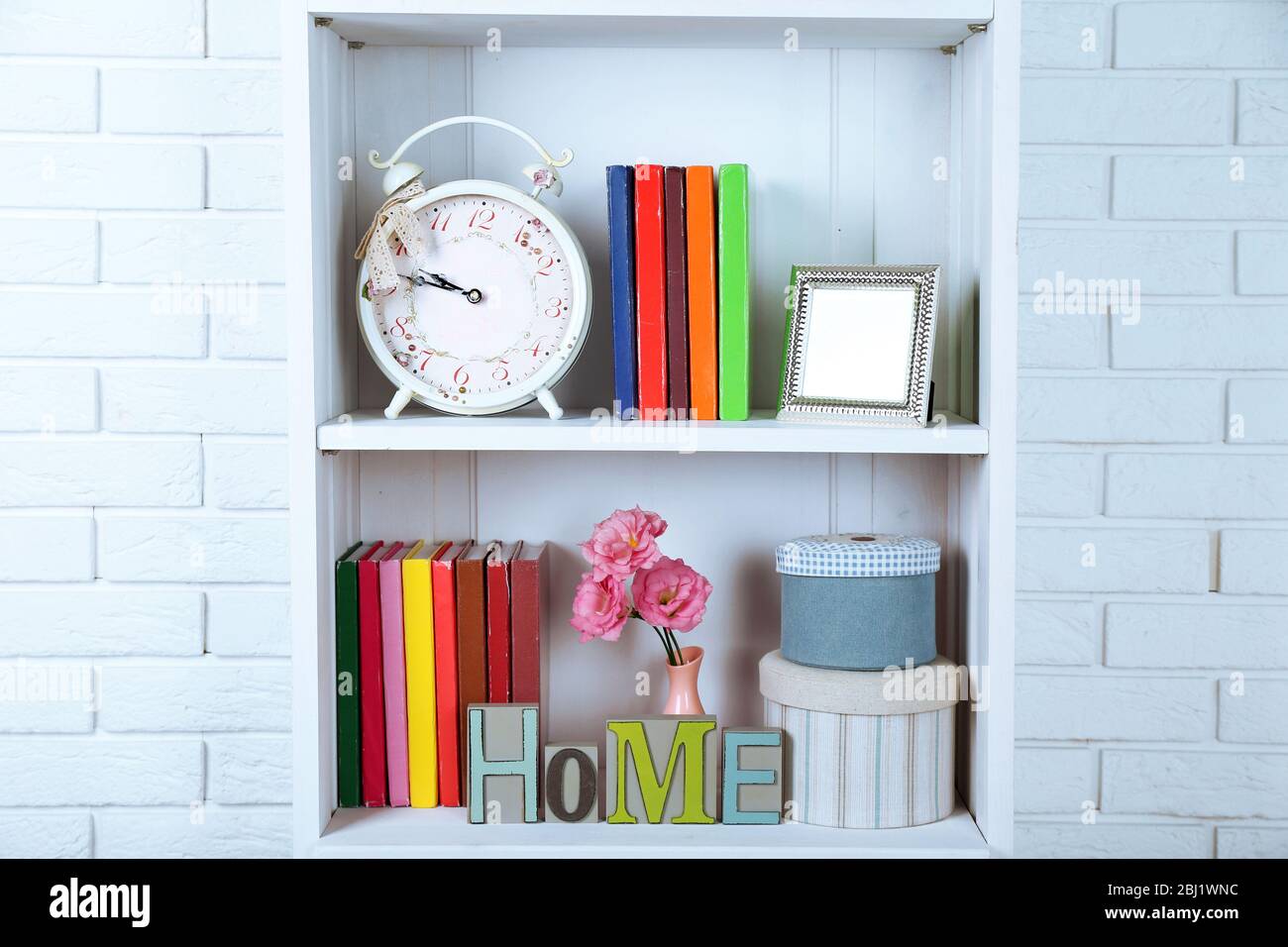 Books and decor on shelves in cupboard Stock Photo - Alamy