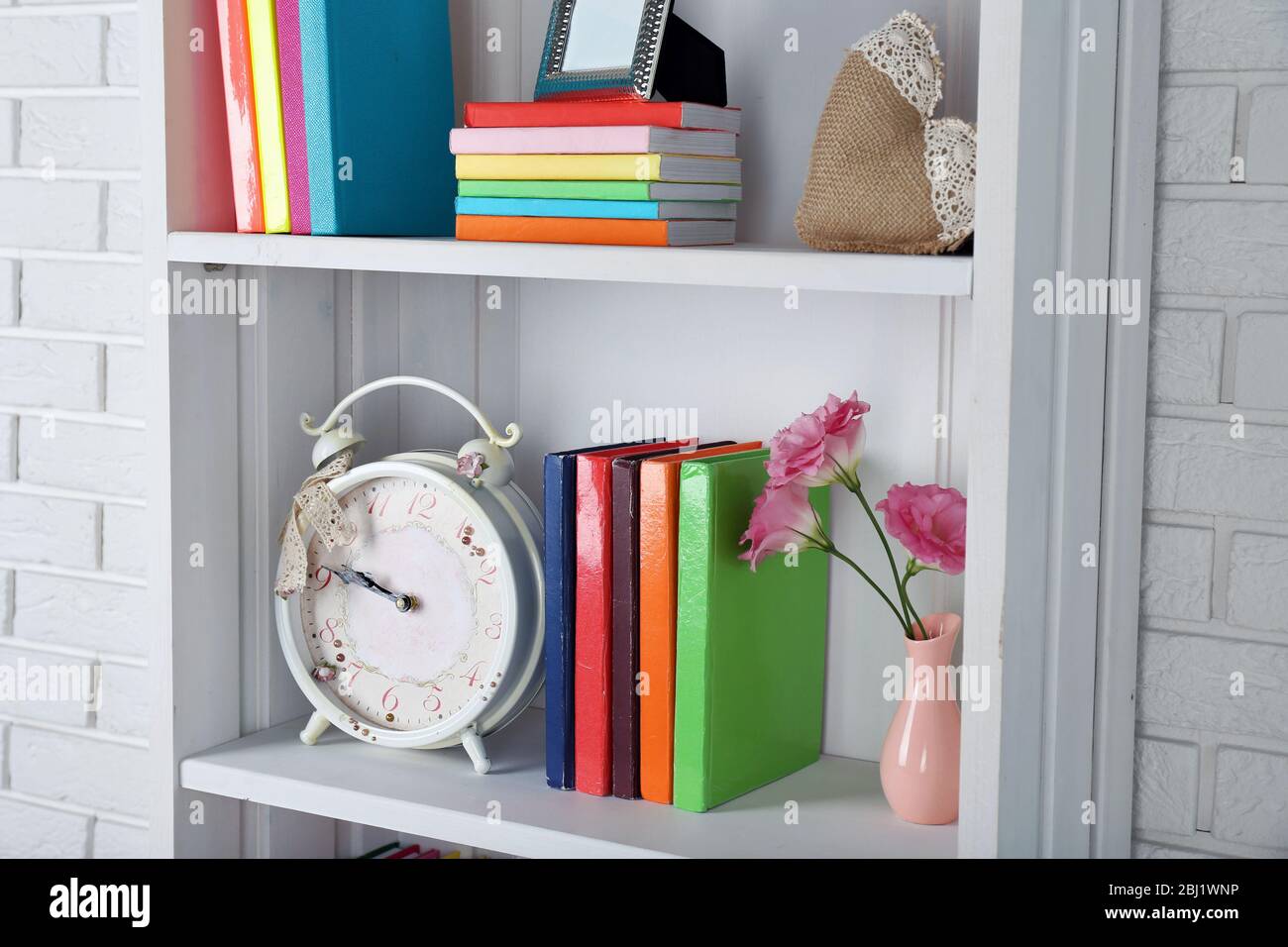Books and decor on shelves in cupboard Stock Photo - Alamy
