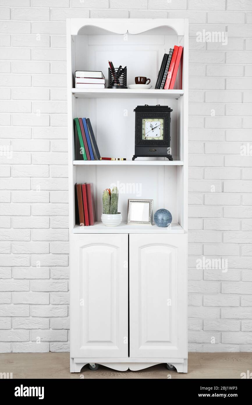 Books and decor on shelves in cupboard Stock Photo - Alamy