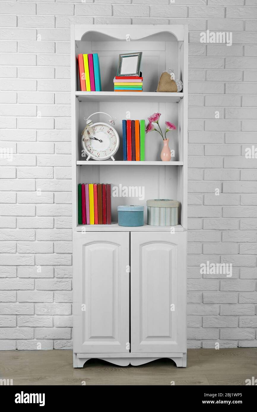 Books and decor on shelves in cupboard Stock Photo - Alamy
