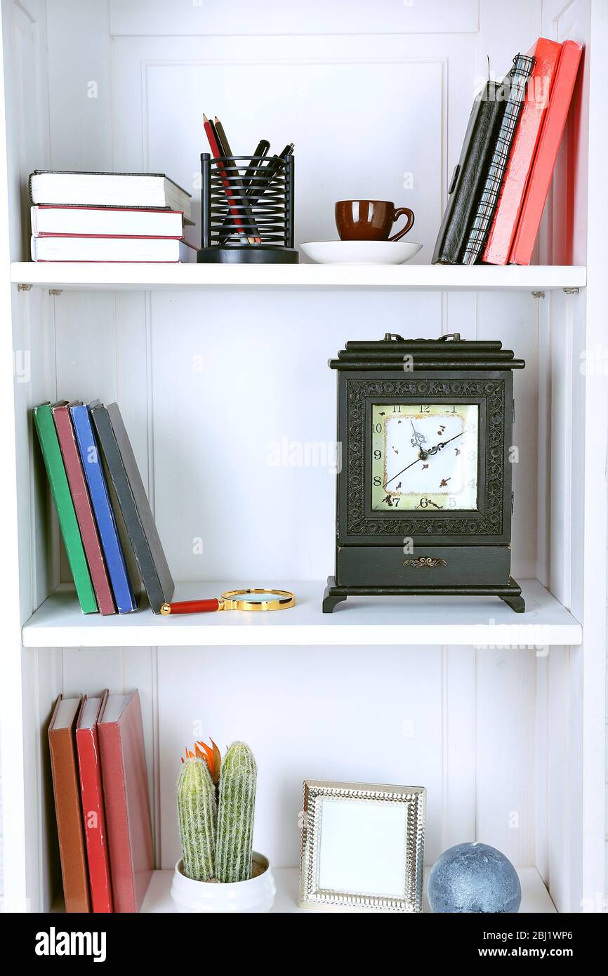 Books and decor on shelves in cupboard Stock Photo - Alamy