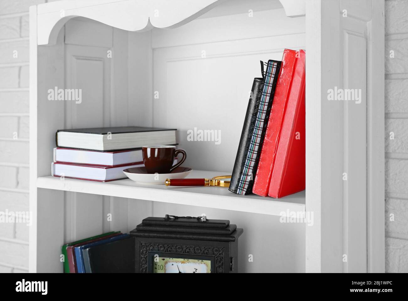 Books and decor on shelves in cupboard Stock Photo - Alamy