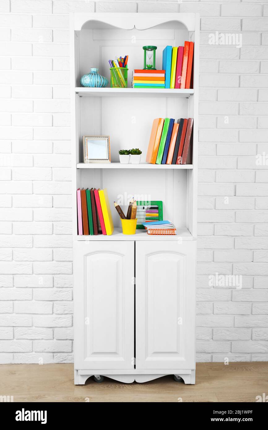 Books and decor on shelves in cupboard Stock Photo - Alamy