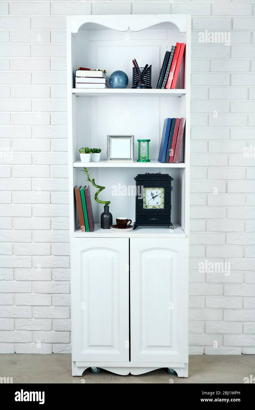 Books and decor on shelves in cupboard Stock Photo - Alamy