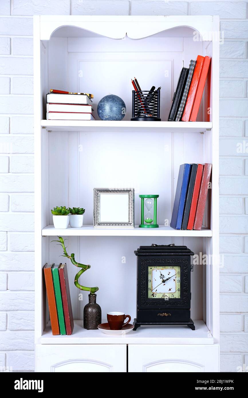 Books and decor on shelves in cupboard Stock Photo - Alamy