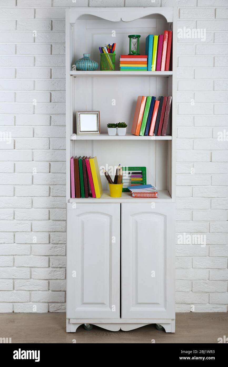 Books and decor on shelves in cupboard Stock Photo - Alamy