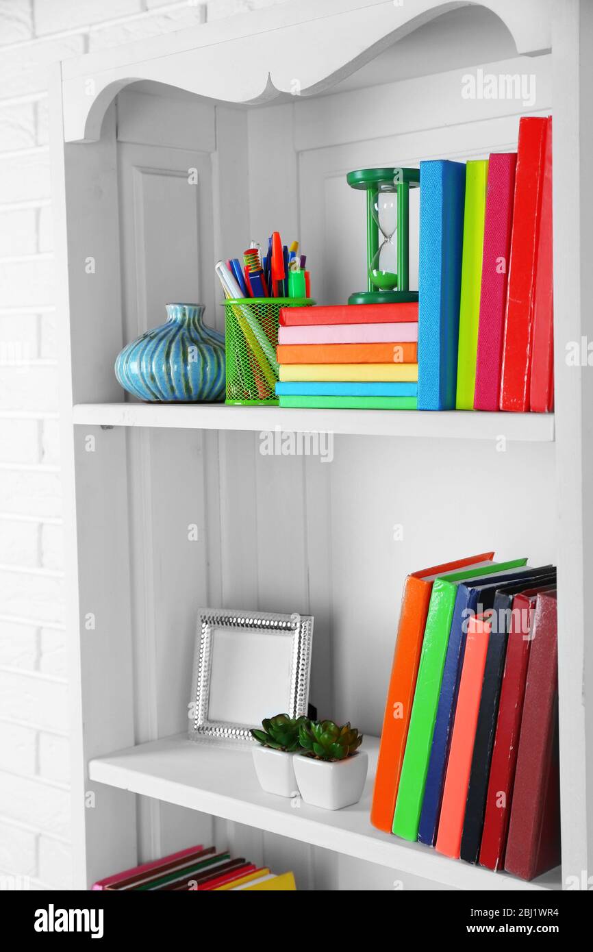 Books and decor on shelves in cupboard Stock Photo - Alamy