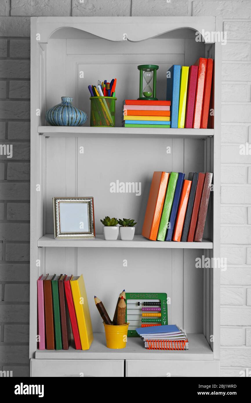 Books and decor on shelves in cupboard Stock Photo - Alamy