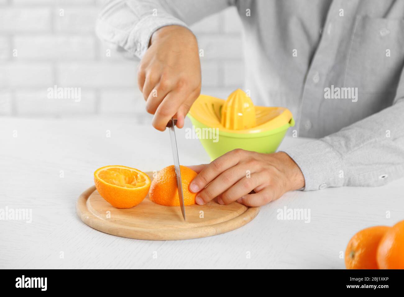 Young man cutting oranges, preparing orange juice Stock Photo - Alamy