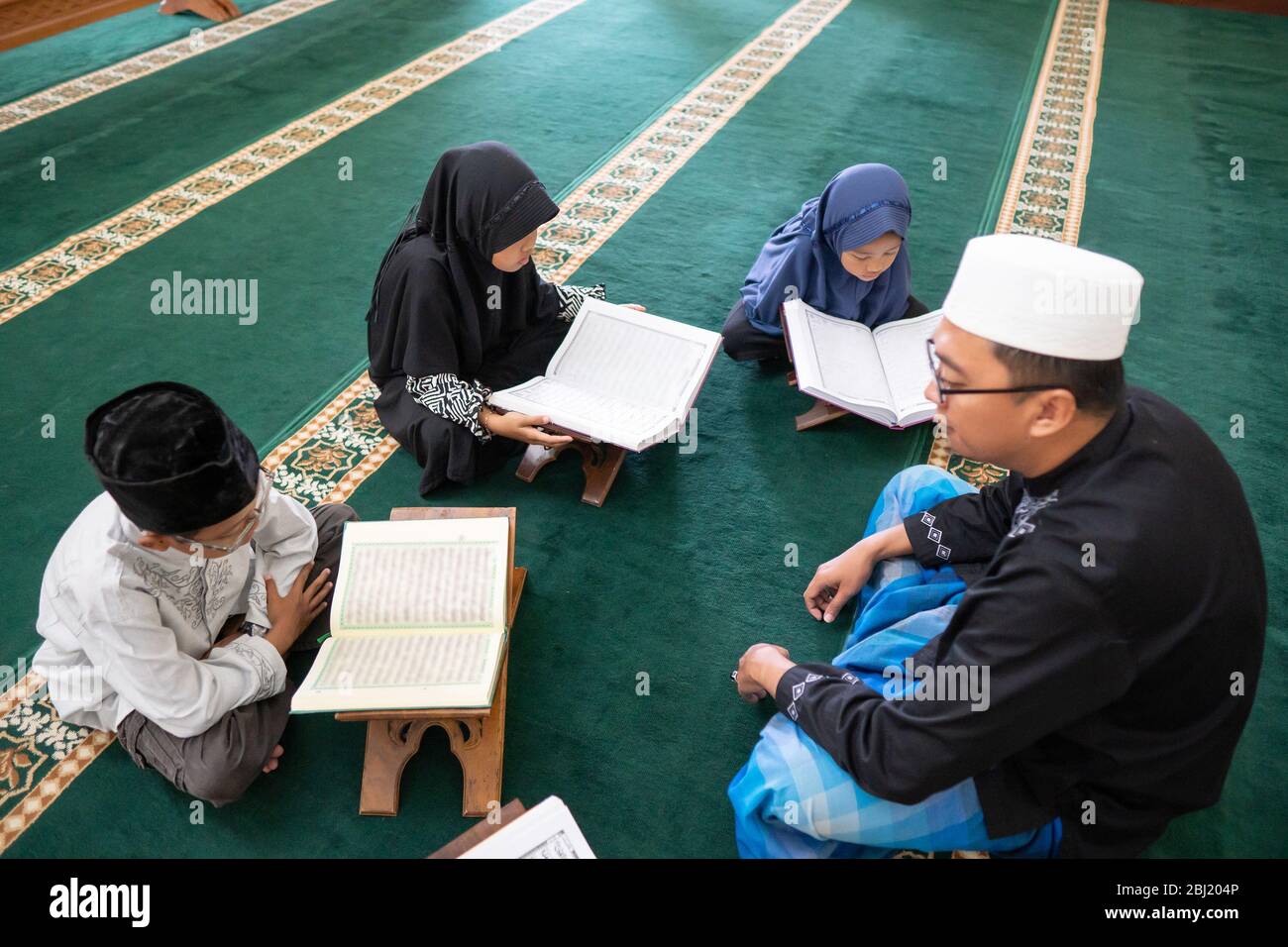 teacher is teaching muslim kid how to read holy quran in the mosque ...