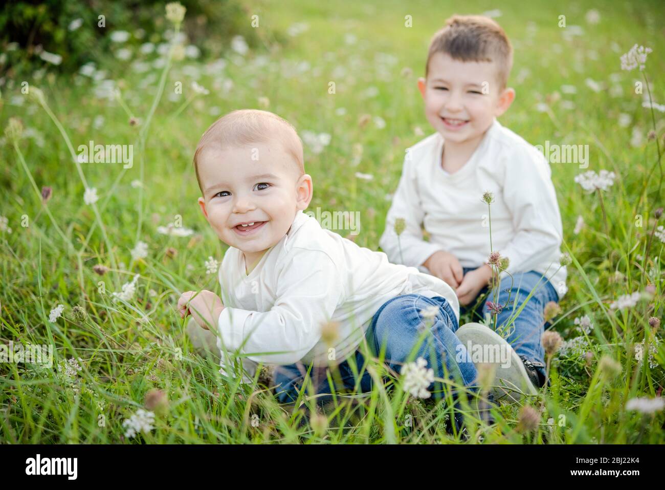 Portrait of two young boys sitting in a meadow, smiling at camera Stock ...