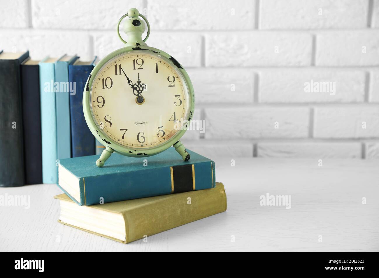 Clock and vintage books, on light wall background Stock Photo - Alamy