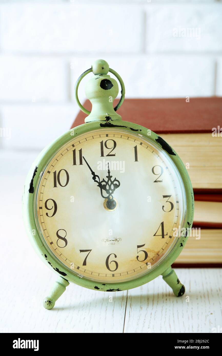 Clock and vintage books, on light wall background Stock Photo - Alamy