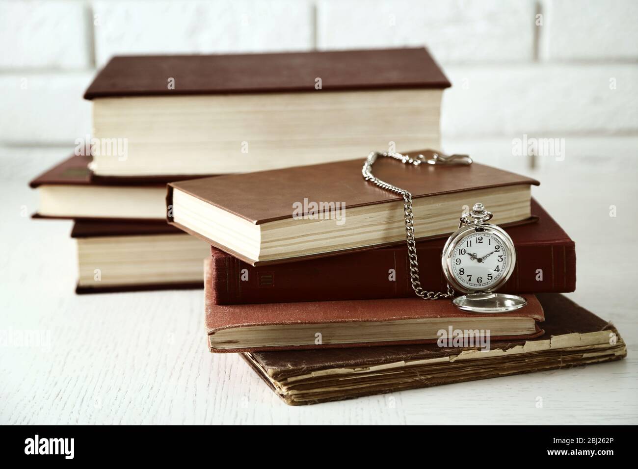 Pocket clock and vintage books, on light wall background Stock Photo ...