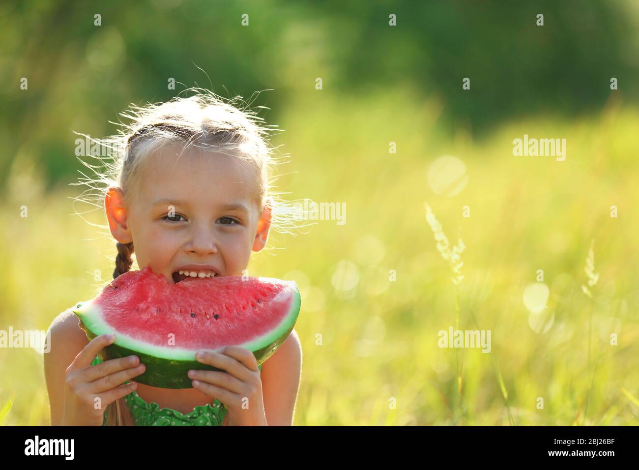 Small girl eating watermelons on lawn Stock Photo - Alamy