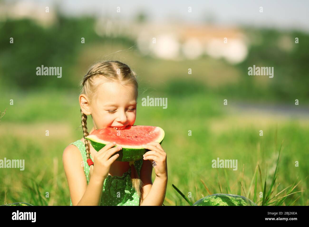 Small girl eating watermelons on lawn Stock Photo - Alamy