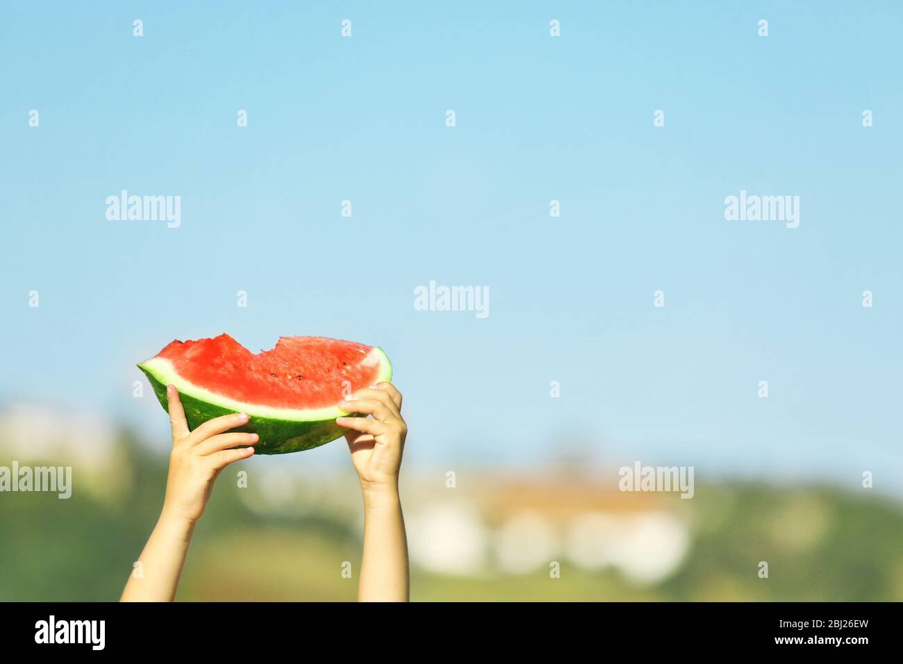 Child hands holding slice of watermelons on blue sky background Stock ...