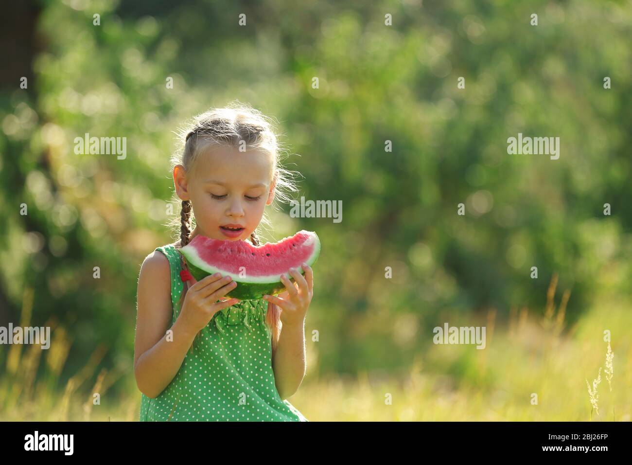 Small girl eating watermelons on lawn Stock Photo - Alamy