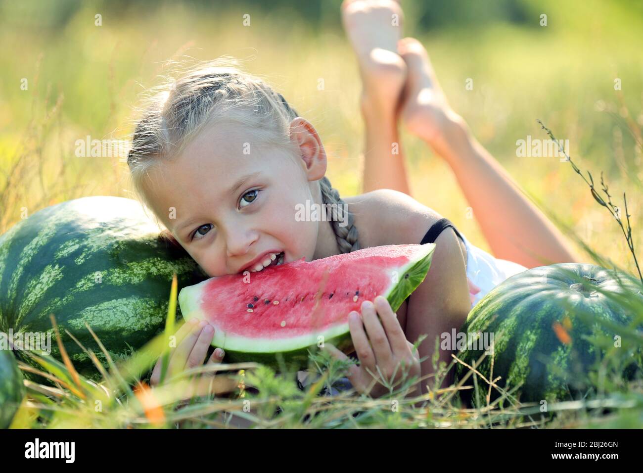 Small girl with watermelons on lawn Stock Photo - Alamy