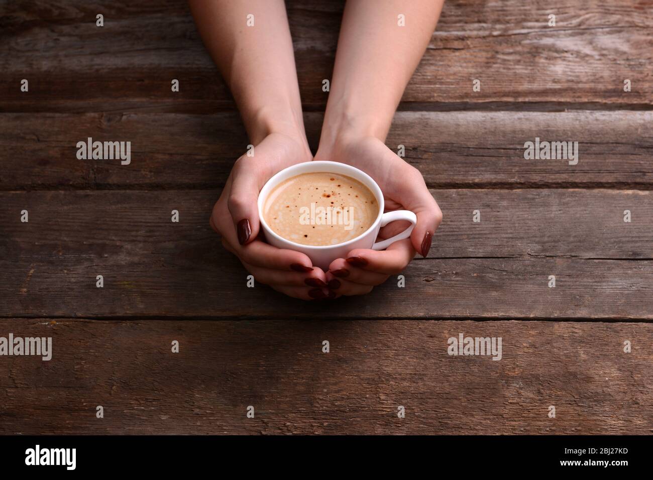 Female hands holding cup of coffee on wooden background Stock Photo - Alamy